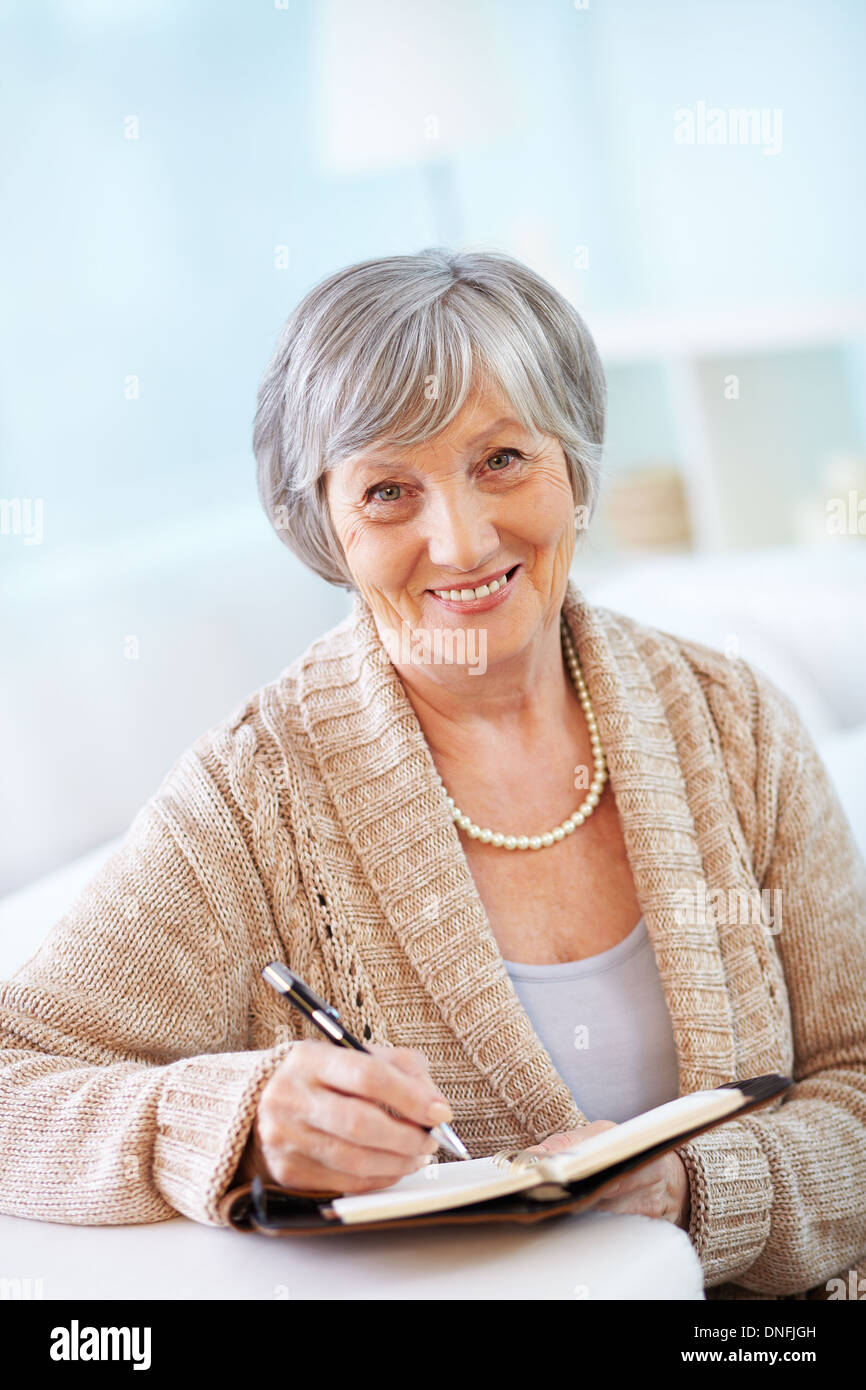 Portrait of aged female with notepad looking at camera with smile Stock ...