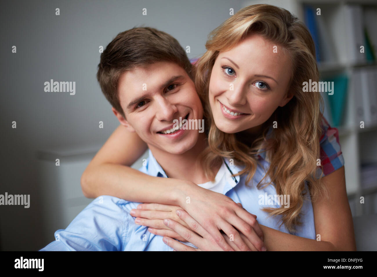 Portrait of amorous young woman embracing her husband, both looking at ...