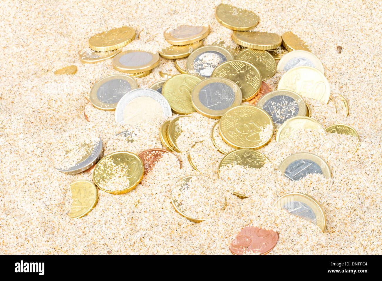 Euro coins in the sand Stock Photo - Alamy