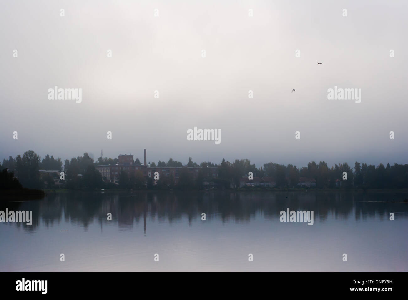 Small town behind a lake on misty overcast morning Stock Photo - Alamy