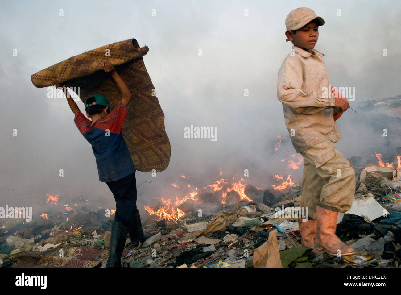 Child laborer boys are working near flaming piles of garbage at the ...
