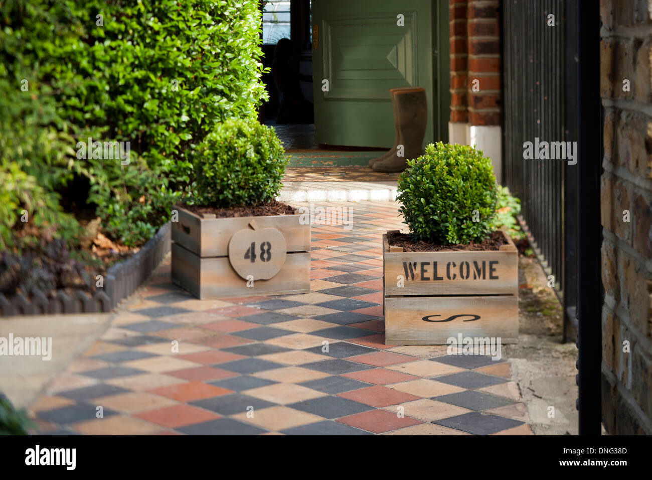 Two potted Box hedge plants, in wooden planters on a path, leading to a ...