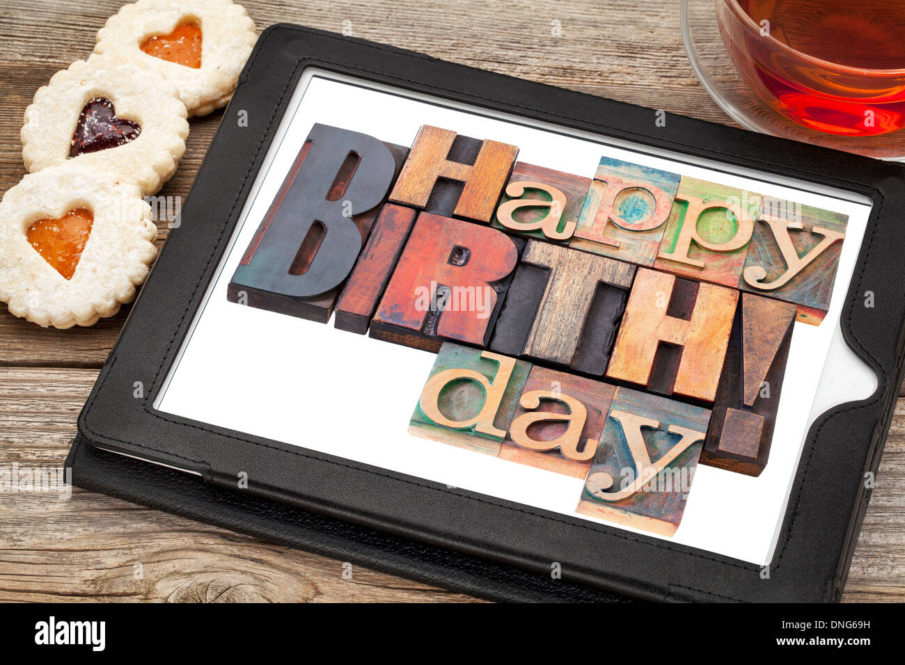 Happy birthday in letterpress wood type on digital tablet with stylus a ...