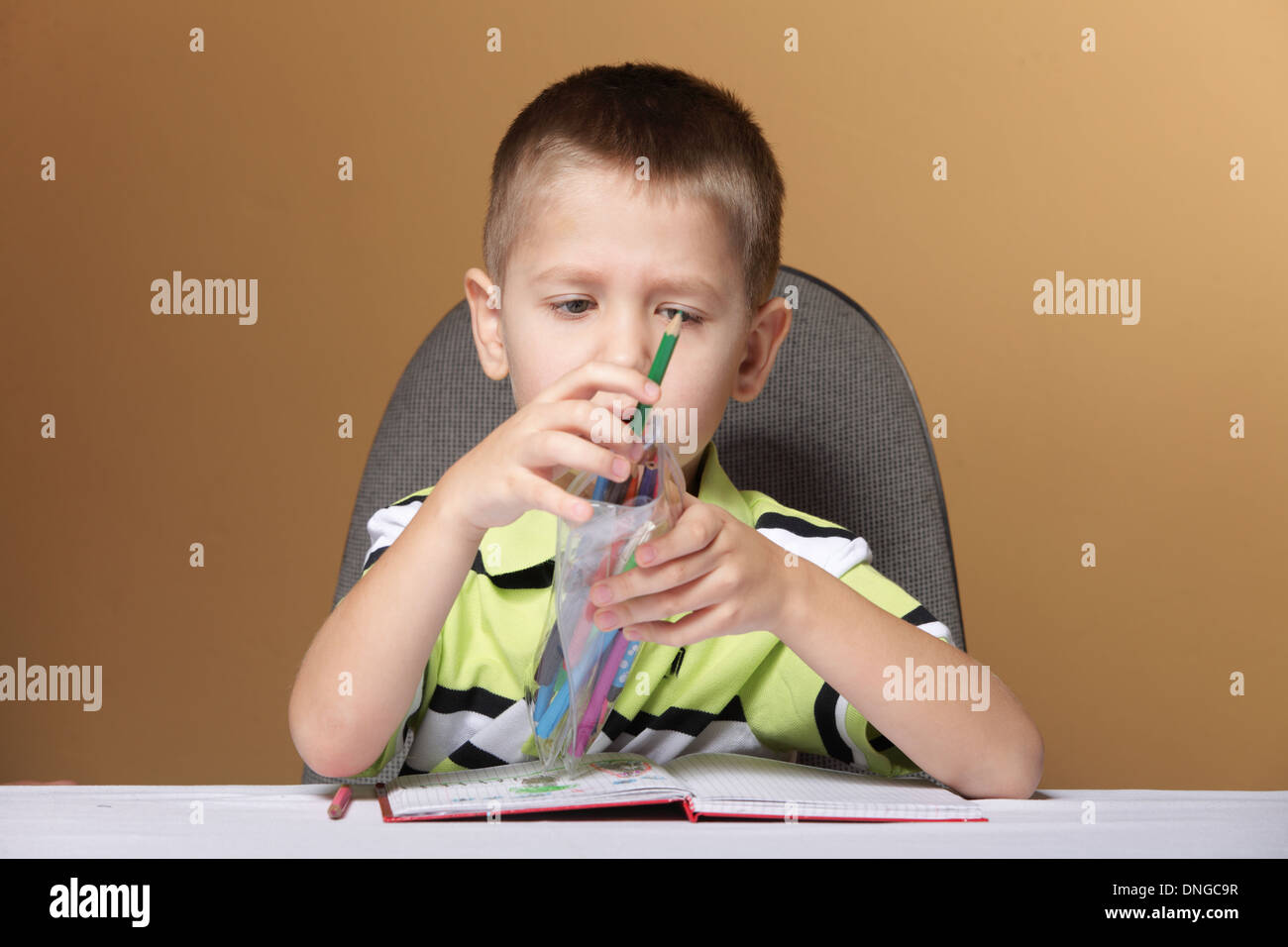 little boy child kid drawing with color pencils on brown background ...