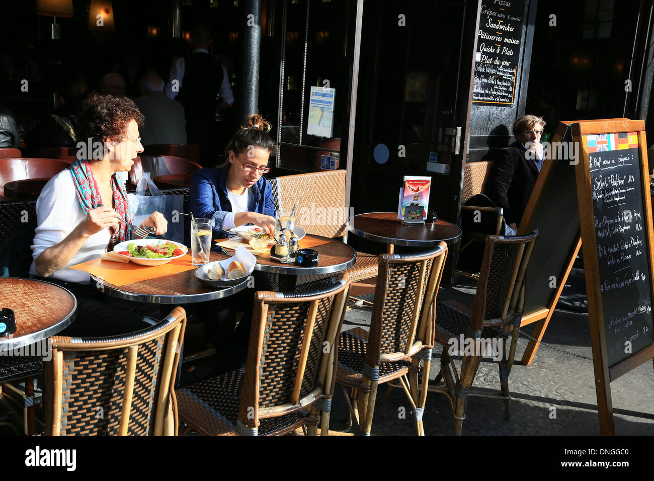 People eating in the sidewalk cafe with traditional circular tables and ...
