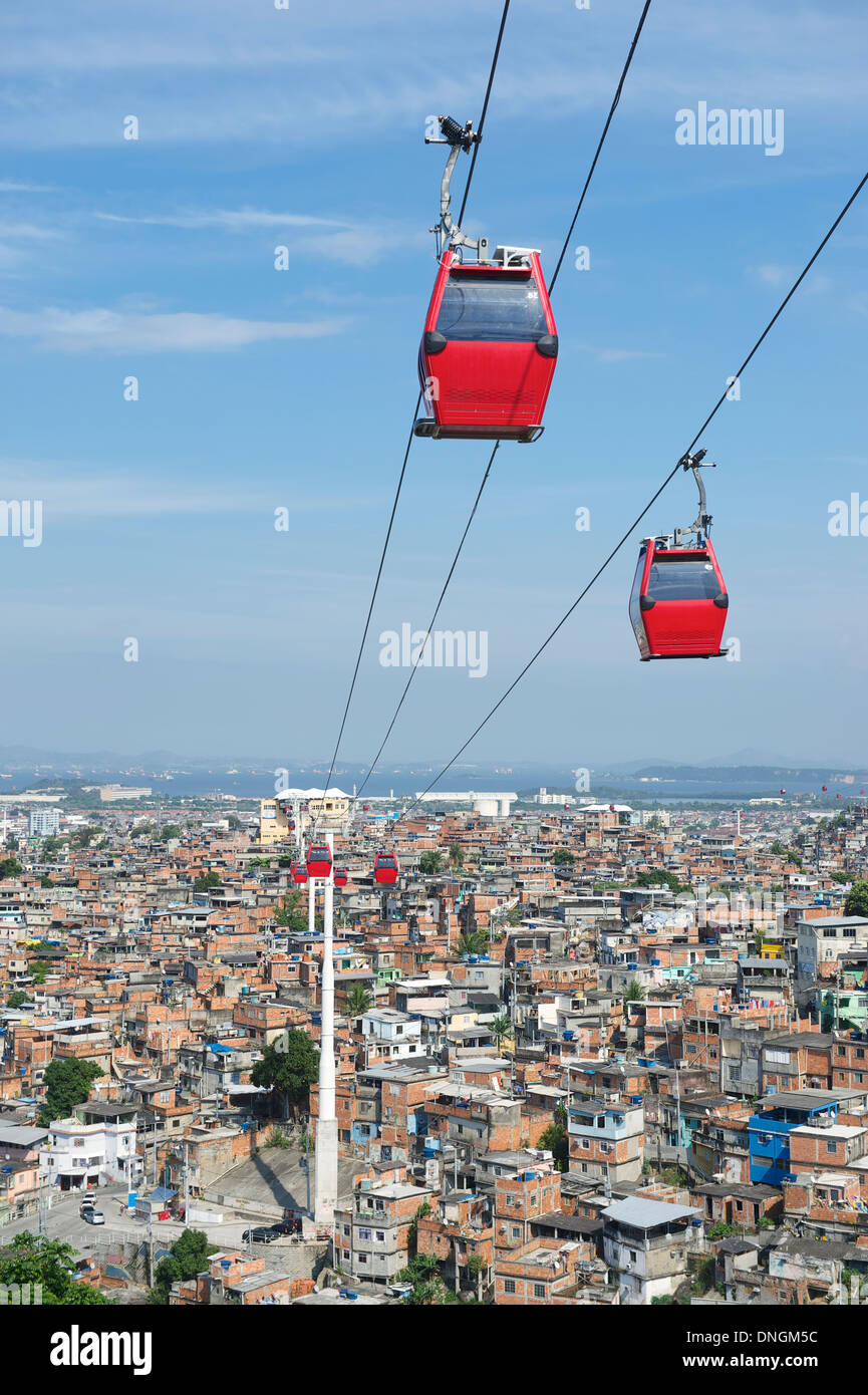 Red cable cars travel in blue sky above Rio de Janeiro favela slum ...