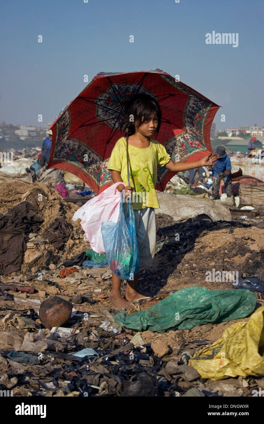 A young child laborer girl is carrying an umbrella to shade herself at ...