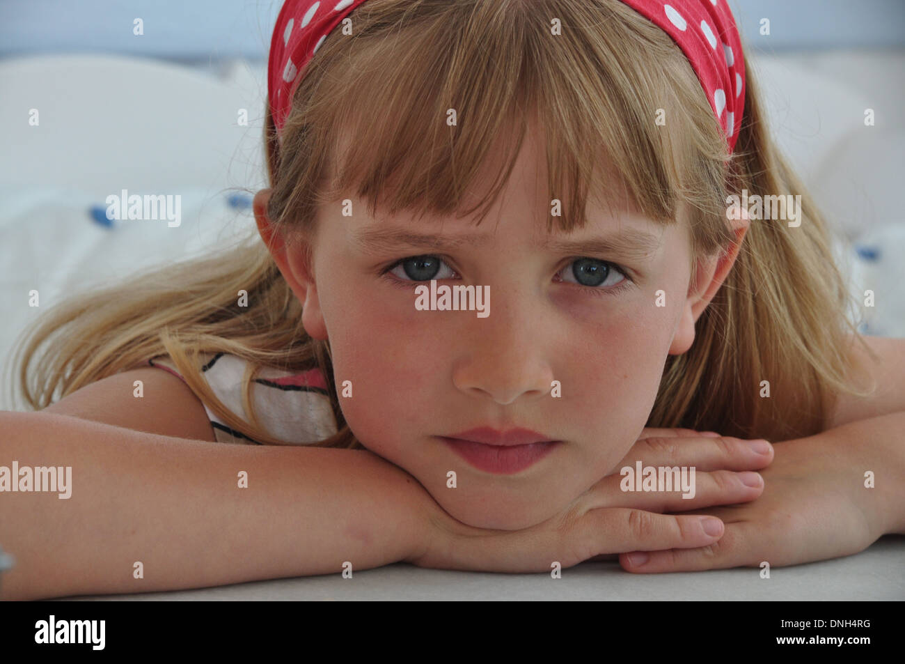 portrait of little blonde girl looking serious and sad looking directly ...