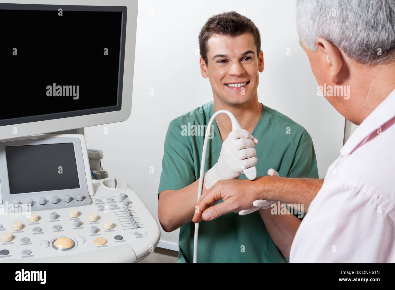 Happy Technician Scanning Male Patient's Hand Stock Photo - Alamy