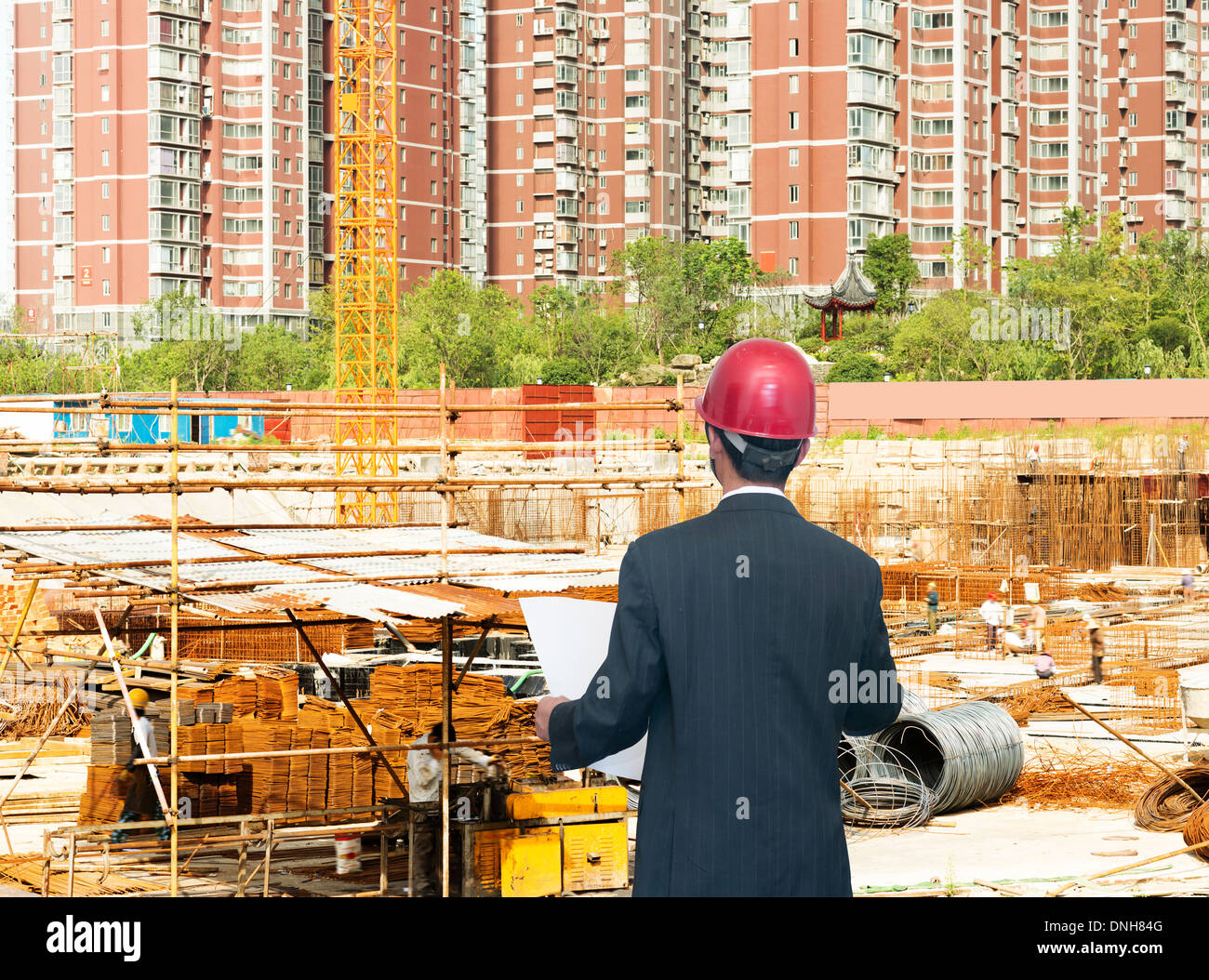 Rear view of architect looking comparing housing project with building ...