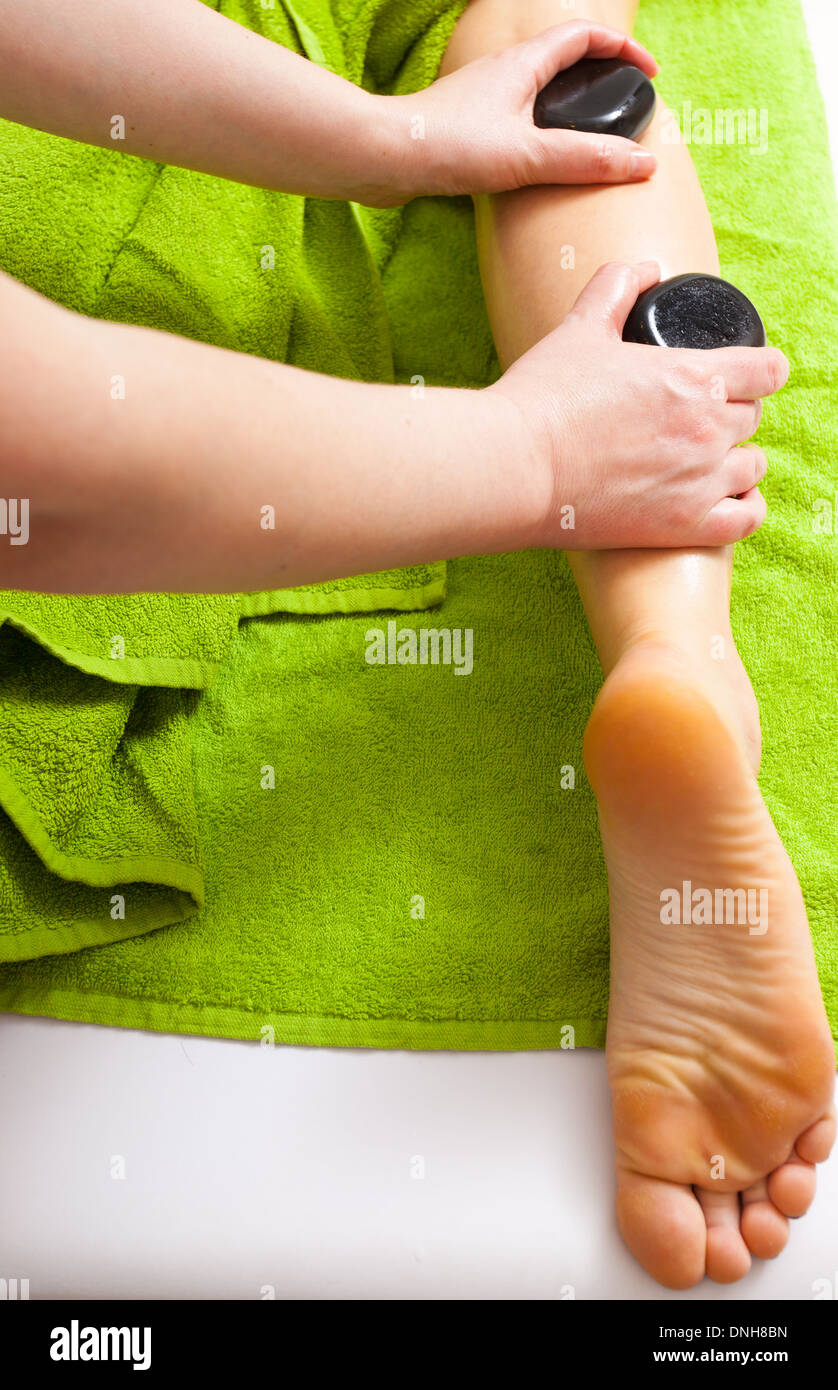 Beauty treatment. Woman relaxing getting spa hot stone therapy legs ...