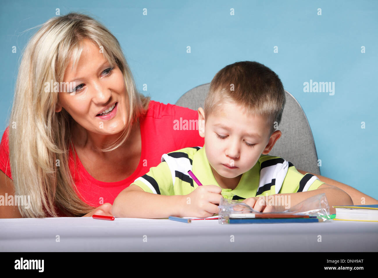 mother and son drawing together, mom helping with homework blue background Stock Photo - Alamy
