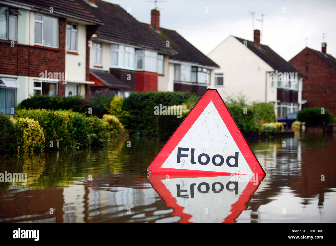 A flood hazard warning sign is pictured in water near flooded homes in ...