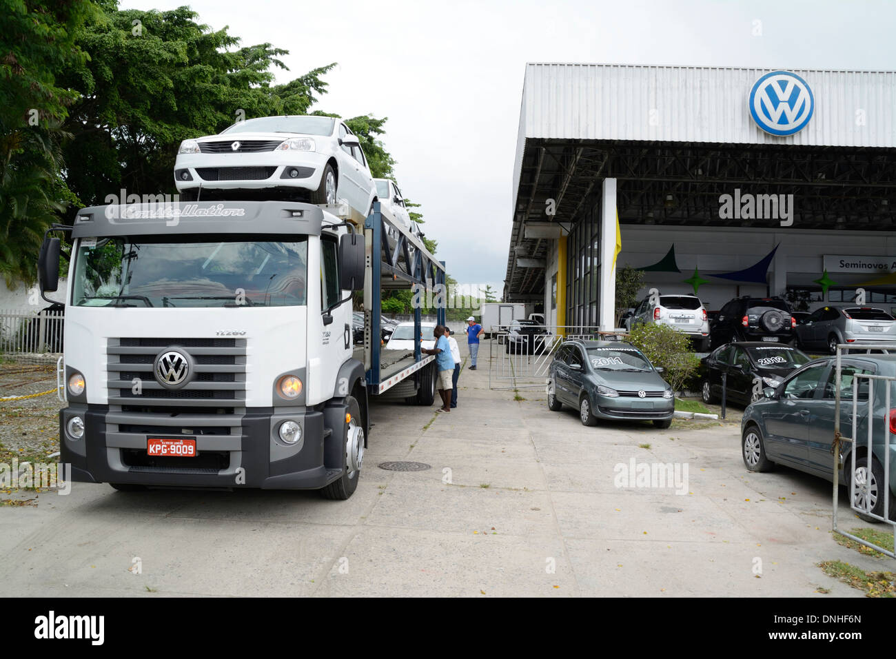 A car carrier delivering a batch of new cars at a Volkswagen dealership ...