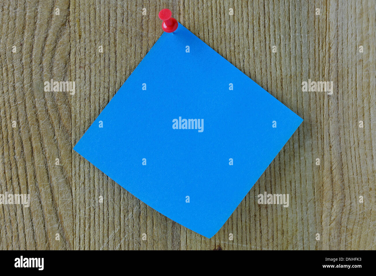 Blue post it note on a wooden background with red thumb-tack Stock ...