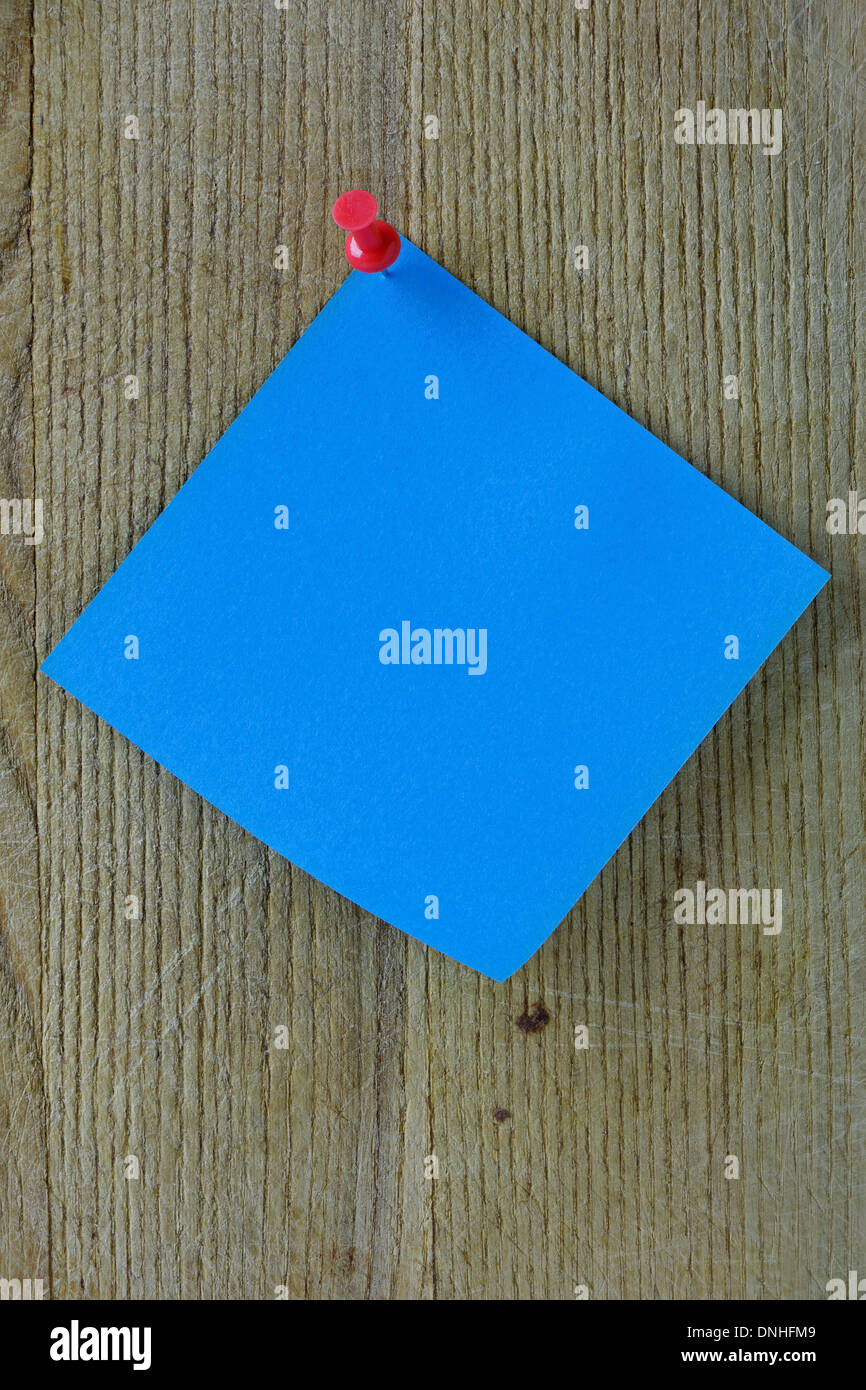 Blue post it note on a wooden background with red thumb-tack Stock ...