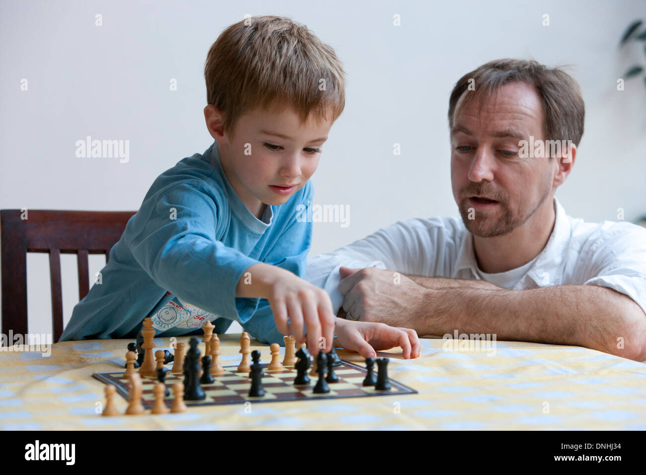 Father is playing chess with his son in the kitchen Stock Photo - Alamy