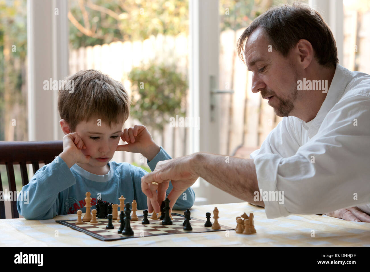 Father is playing chess with his son in the kitchen Stock Photo - Alamy