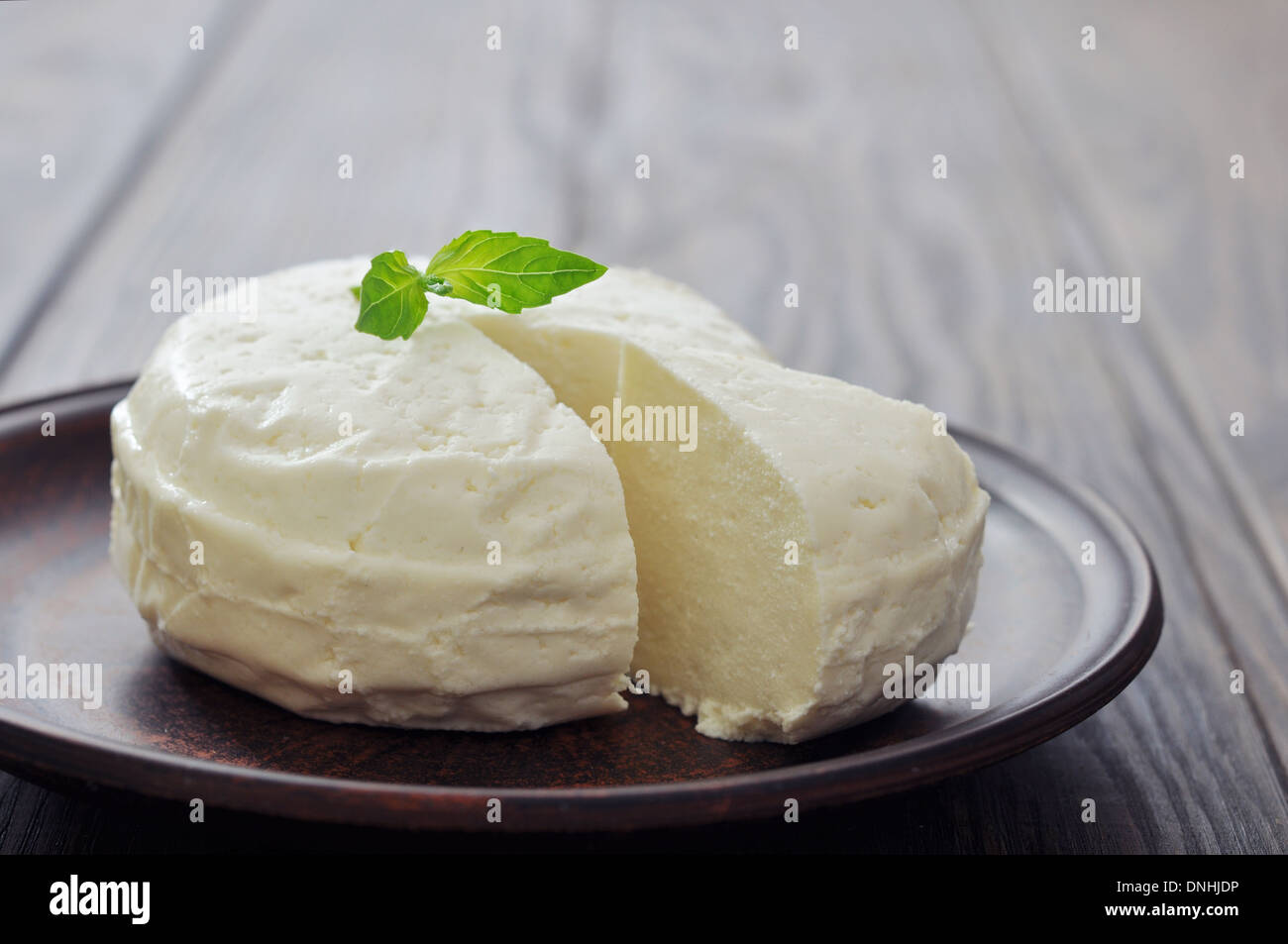 Round cheese on plate on wooden background Stock Photo - Alamy