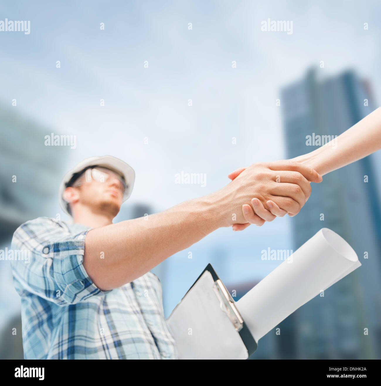 builder with blueprint shaking partner hand Stock Photo - Alamy