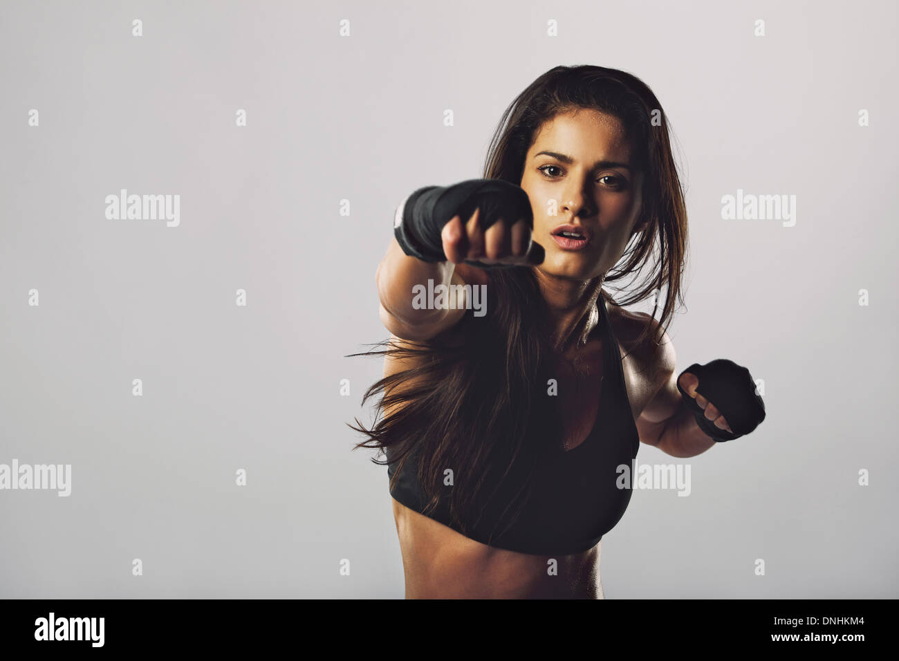 Portrait of hispanic female practicing boxing looking at camera against ...