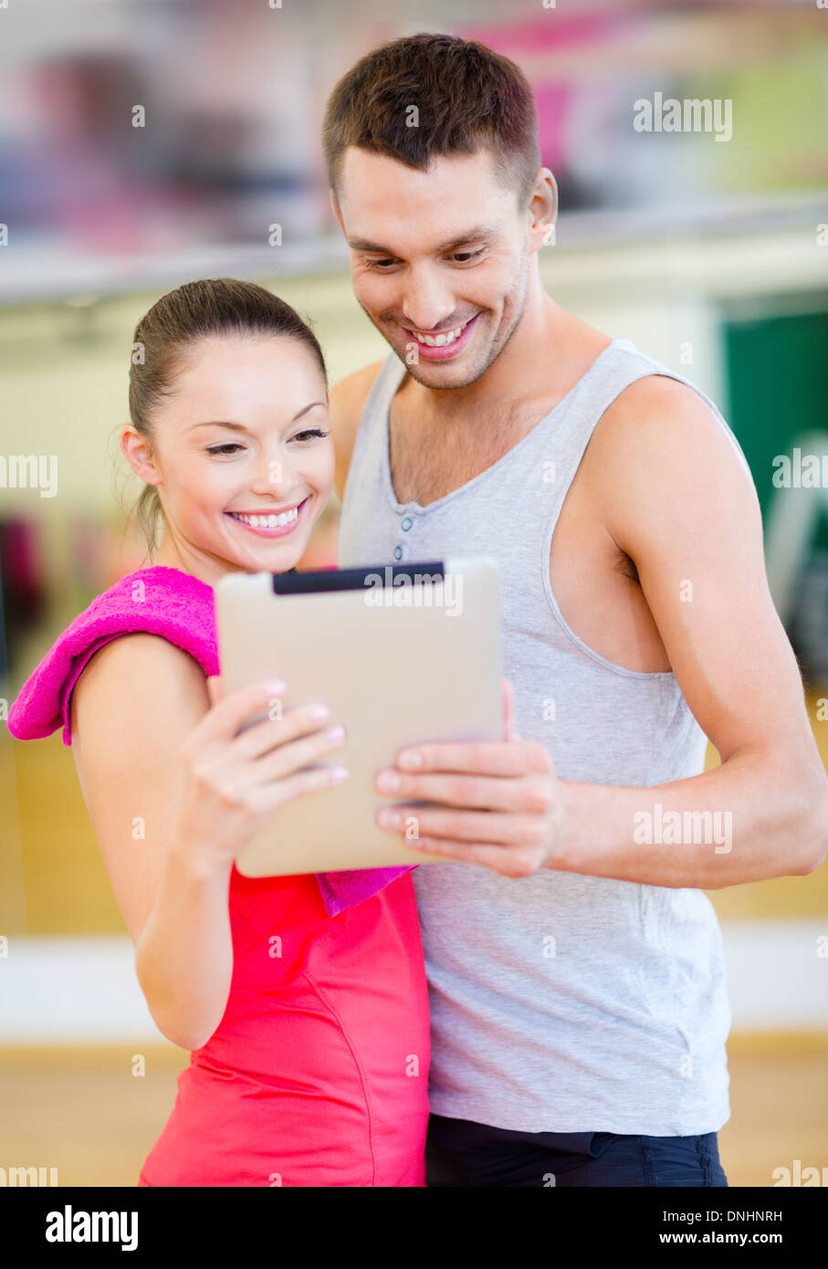 two smiling people with tablet pc in the gym Stock Photo - Alamy