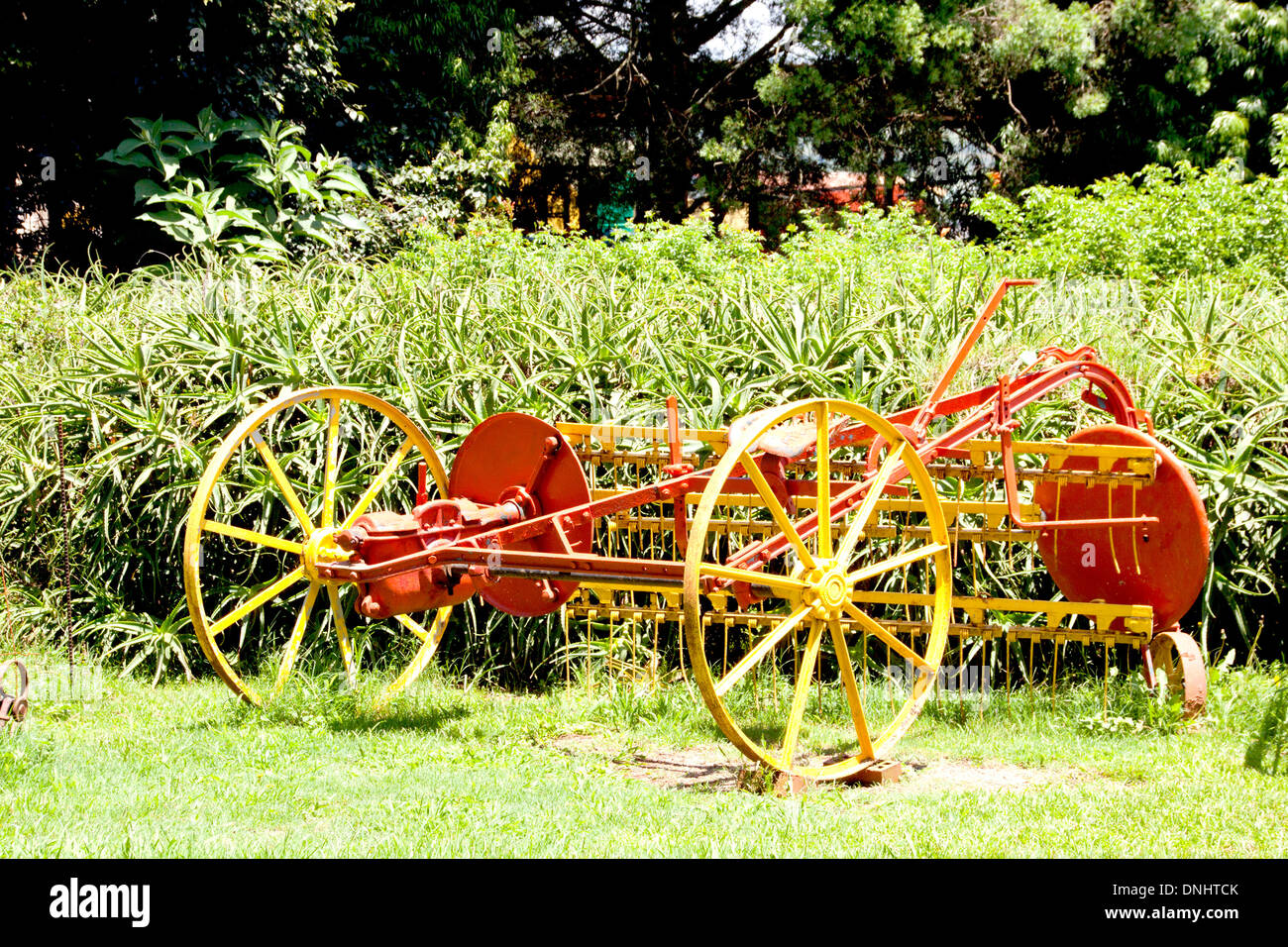 restored vintage farm implement painted yellow and red Stock Photo - Alamy