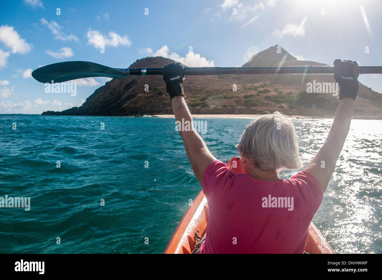Mature woman kayaking near the Mokulua Islands-paddle raised in triumph ...