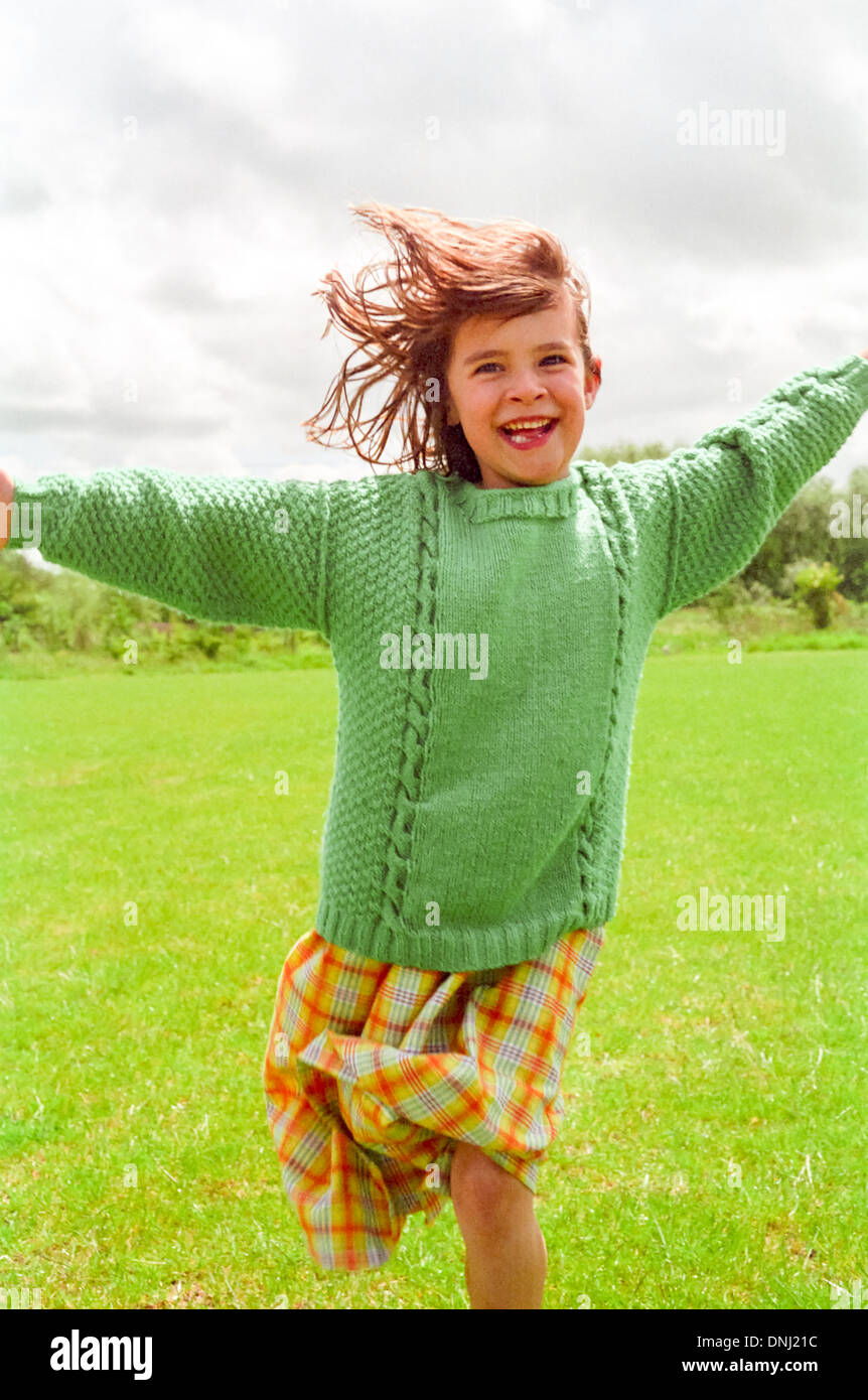 Smiling 7 year old girl with arms flung out and hair flying, running ...