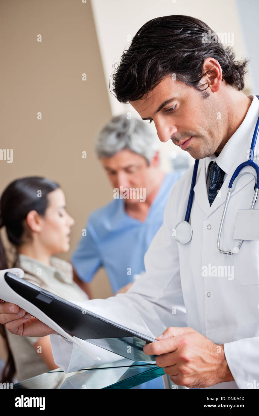 Doctor Reading Document At Reception Stock Photo - Alamy