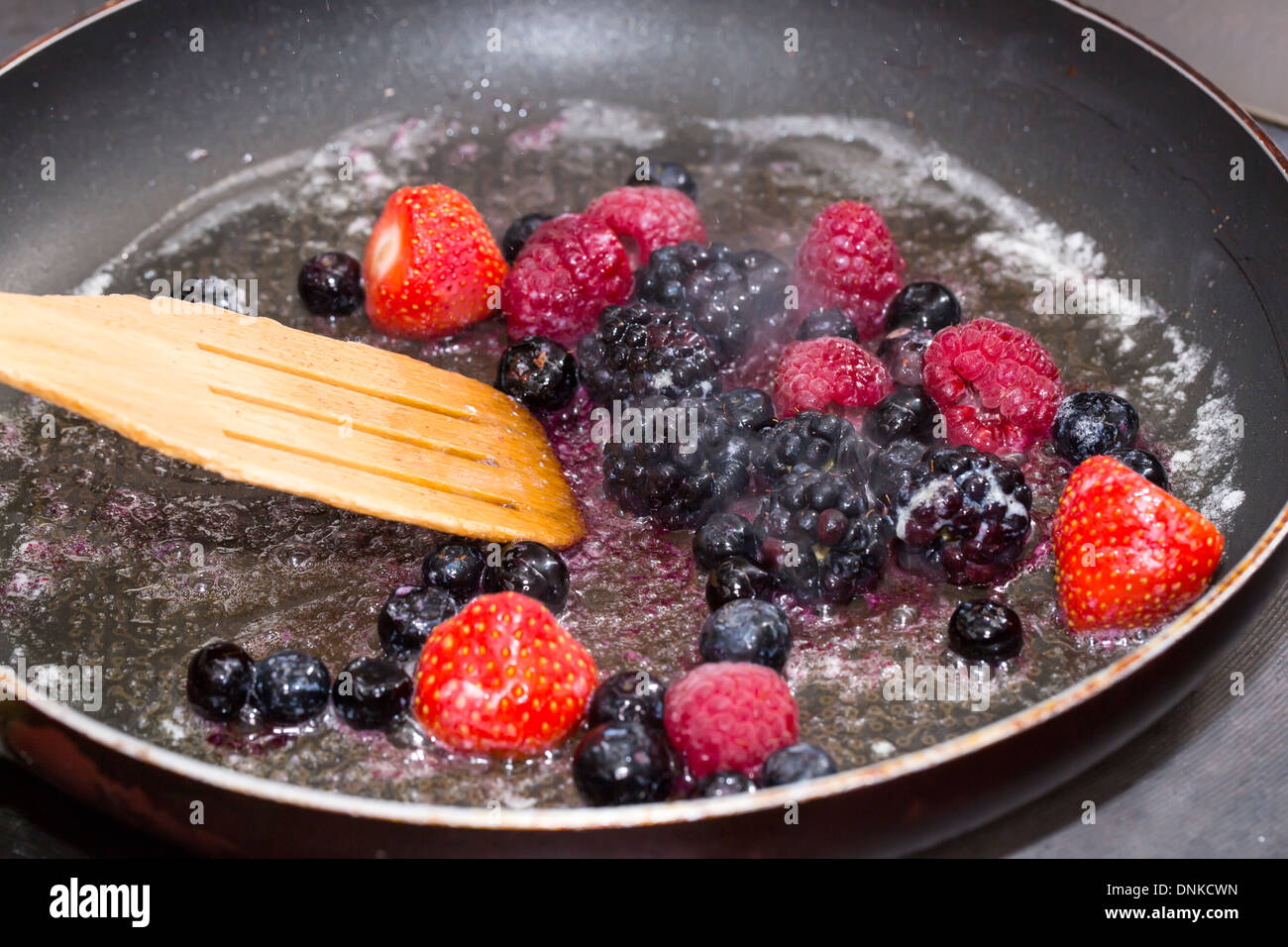 cooking berries in a pan in the kitchen at the restaurant Stock Photo ...