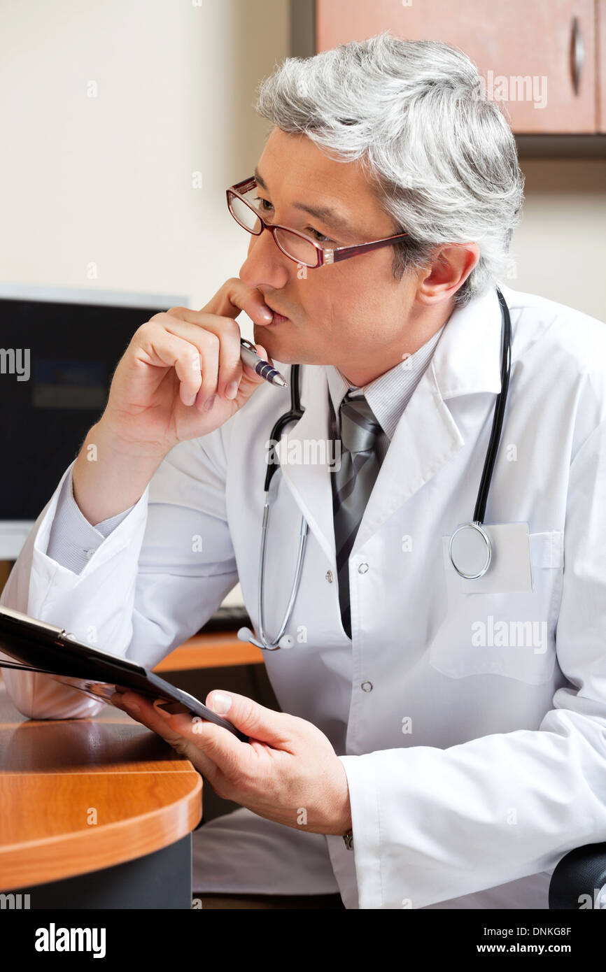 Mature doctor thinking holding hi-res stock photography and images - Alamy