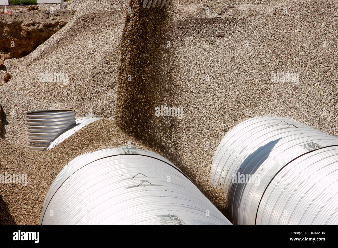 Gravel backfill being placed around stormwater storage metal cisterns ...
