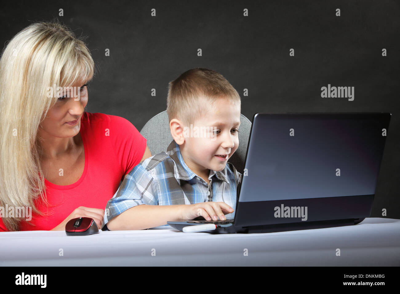 mother with son together looking on the laptop computer black ...