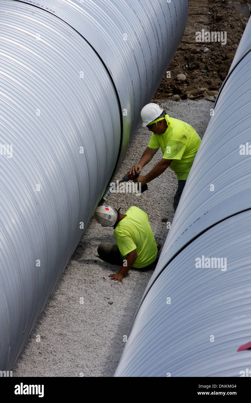 Construction men working on installing stormwater retention pipes ...