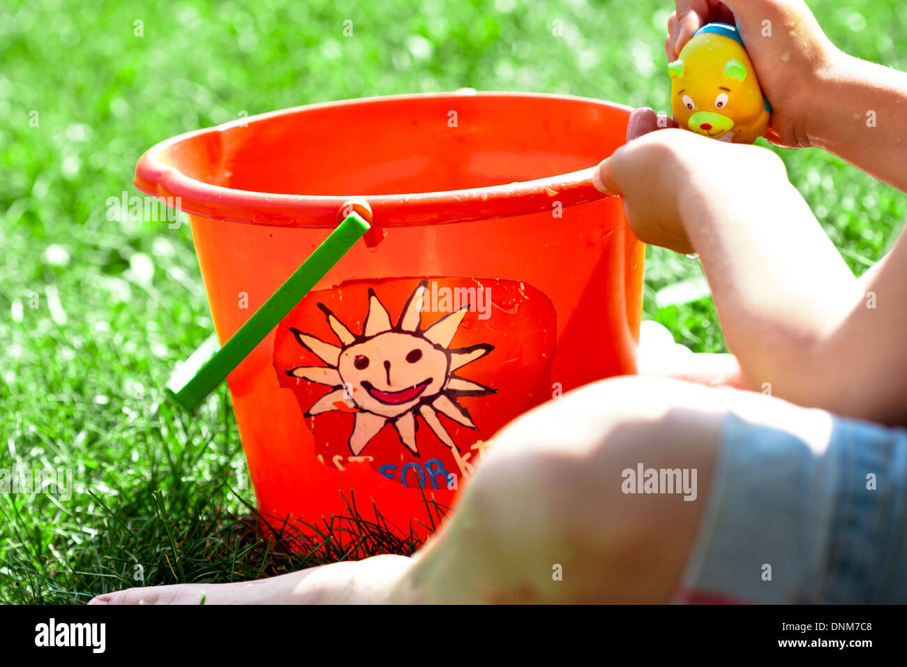Child plays with water and a bucket in the garden Stock Photo - Alamy