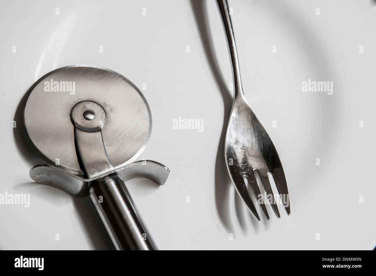 Pizza Cutter and Fork on White Plate, High Angle View Stock Photo - Alamy