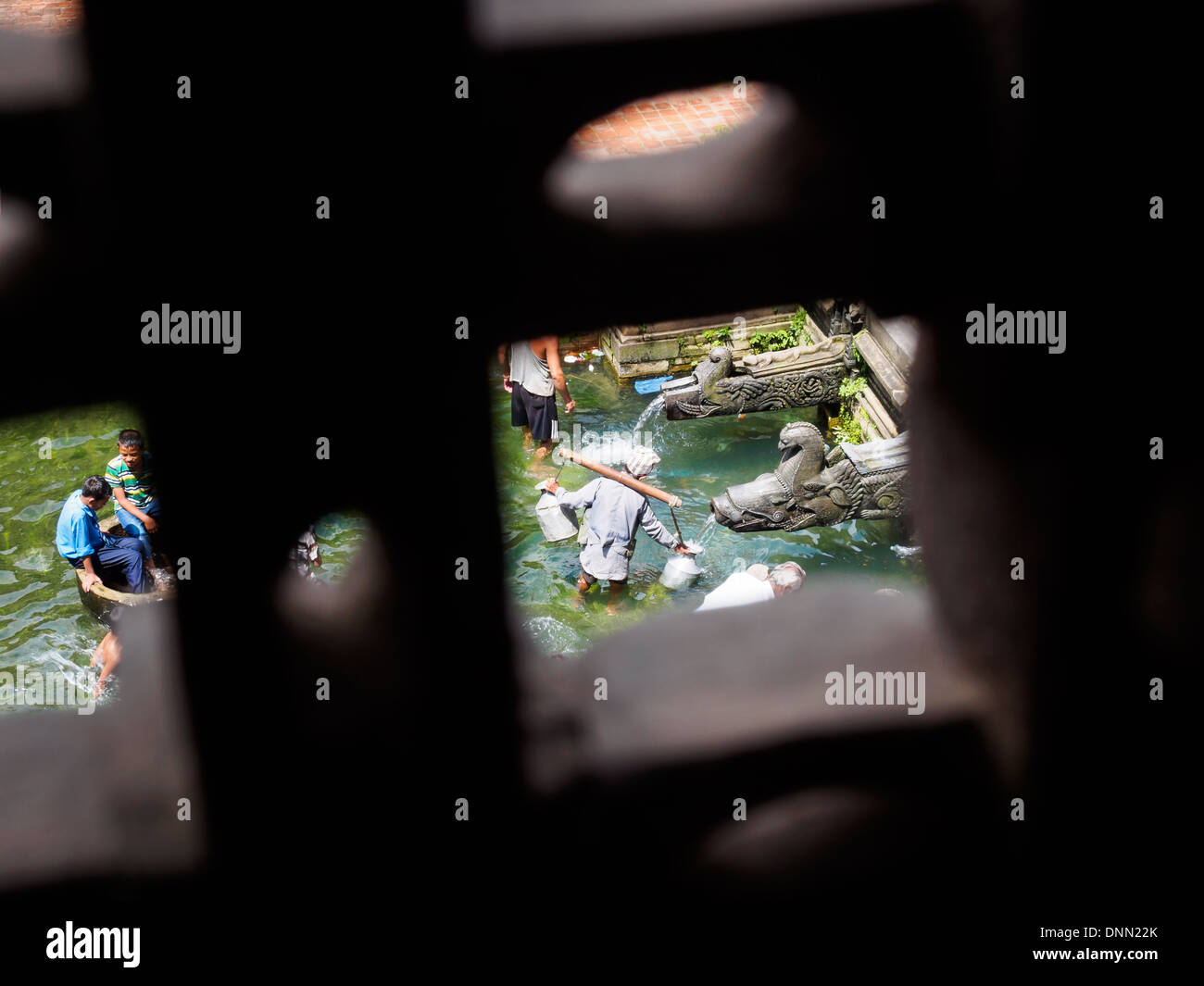 View through wooden window to ancient stone water tap in Patan, Nepal ...