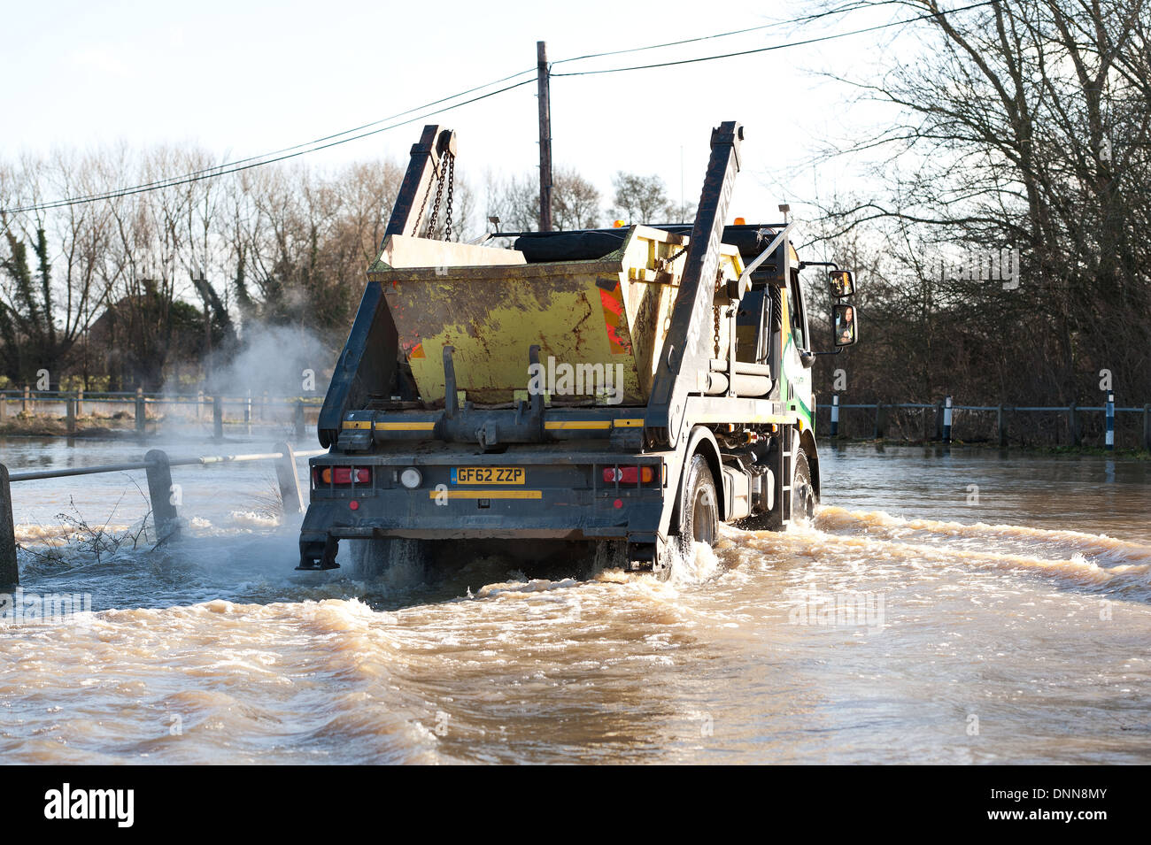 Skip lorry vehicle truck travels down submerged Hampstead lane road ...