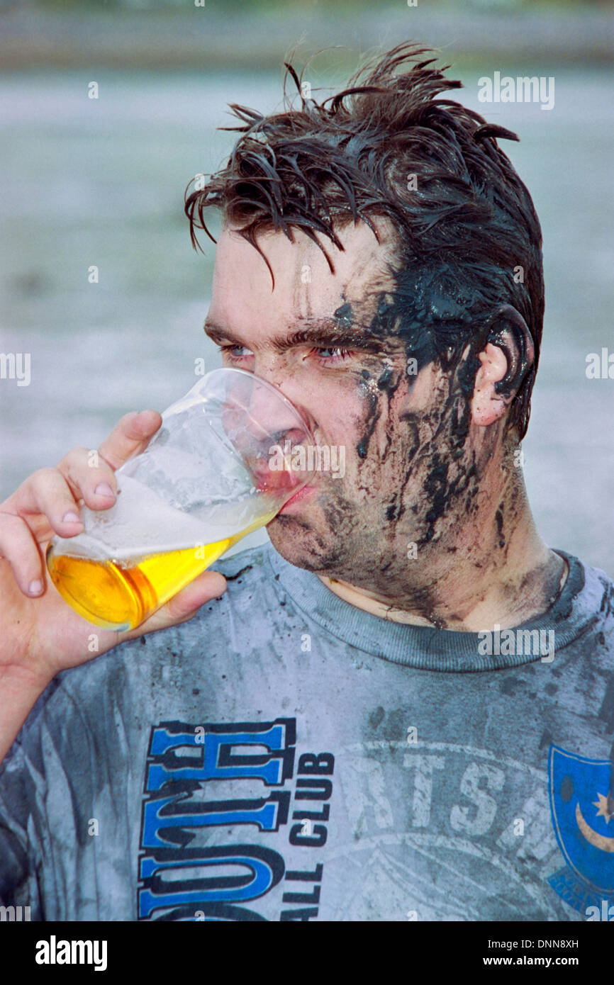 man having a pint of beer after traditional game of mud football on ...