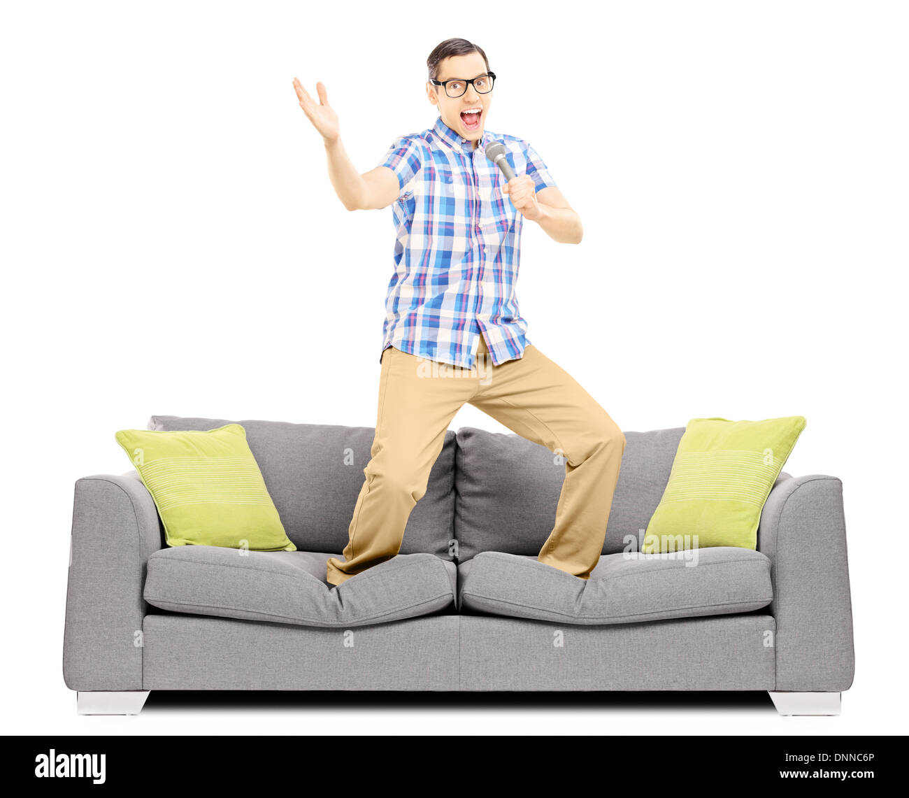 Smiling guy with microphone singing and standing on a modern sofa Stock ...