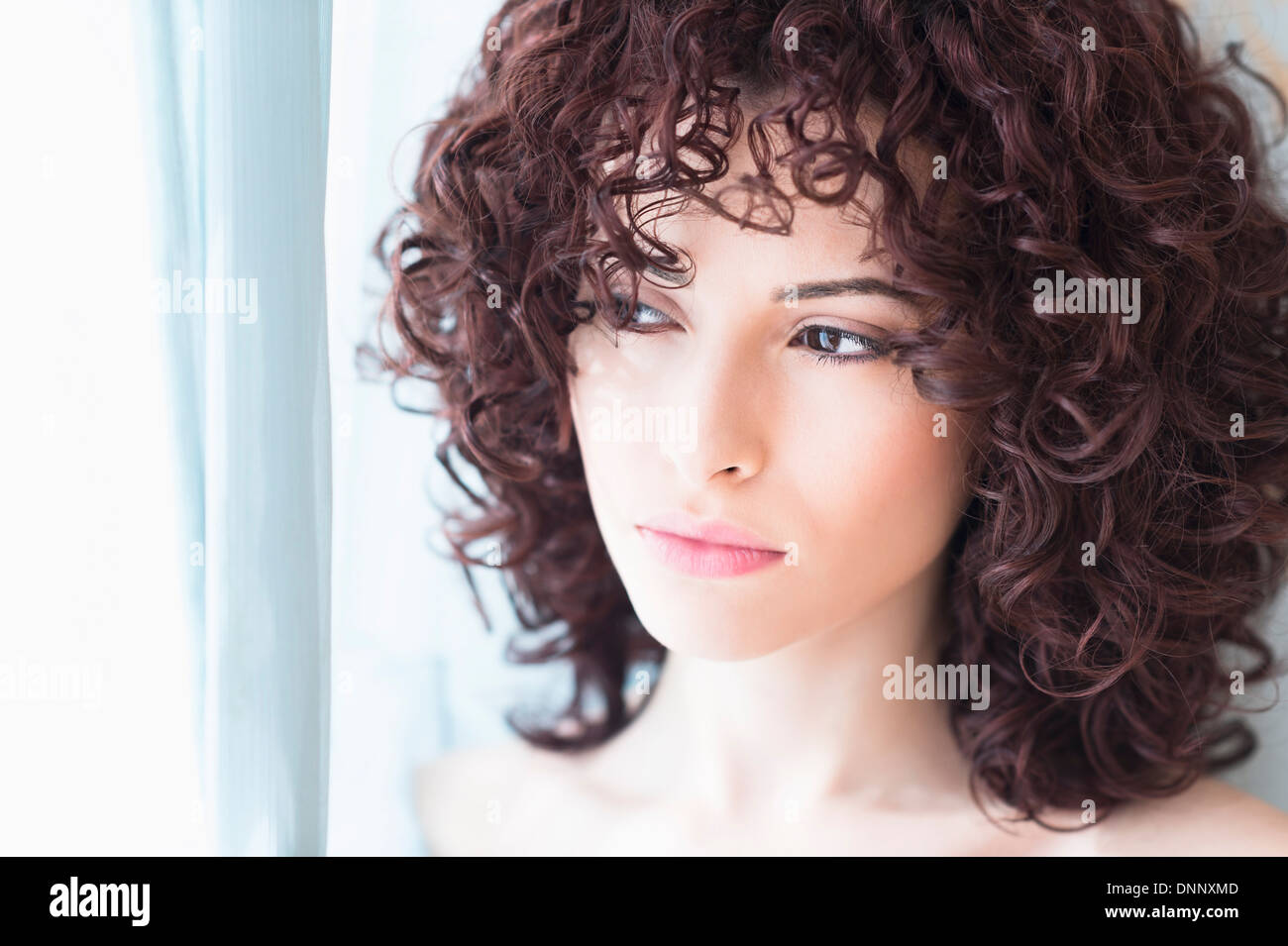 Beautiful woman looking through window Stock Photo - Alamy