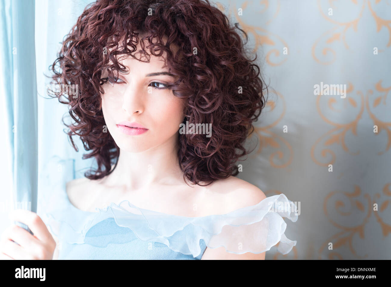 Beautiful woman looking through window Stock Photo - Alamy