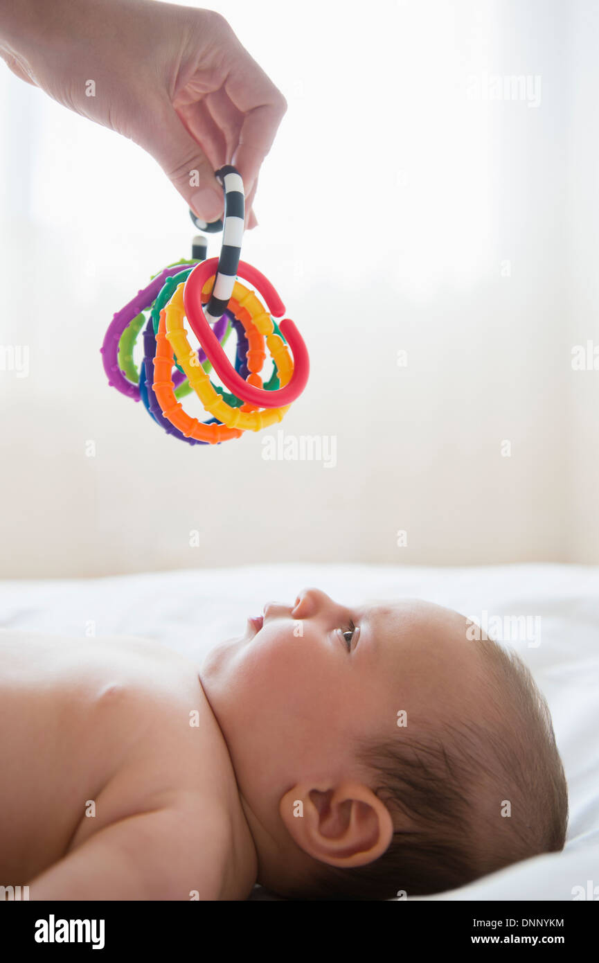 Hand holding colorful toy above baby girl (2-5 months Stock Photo - Alamy