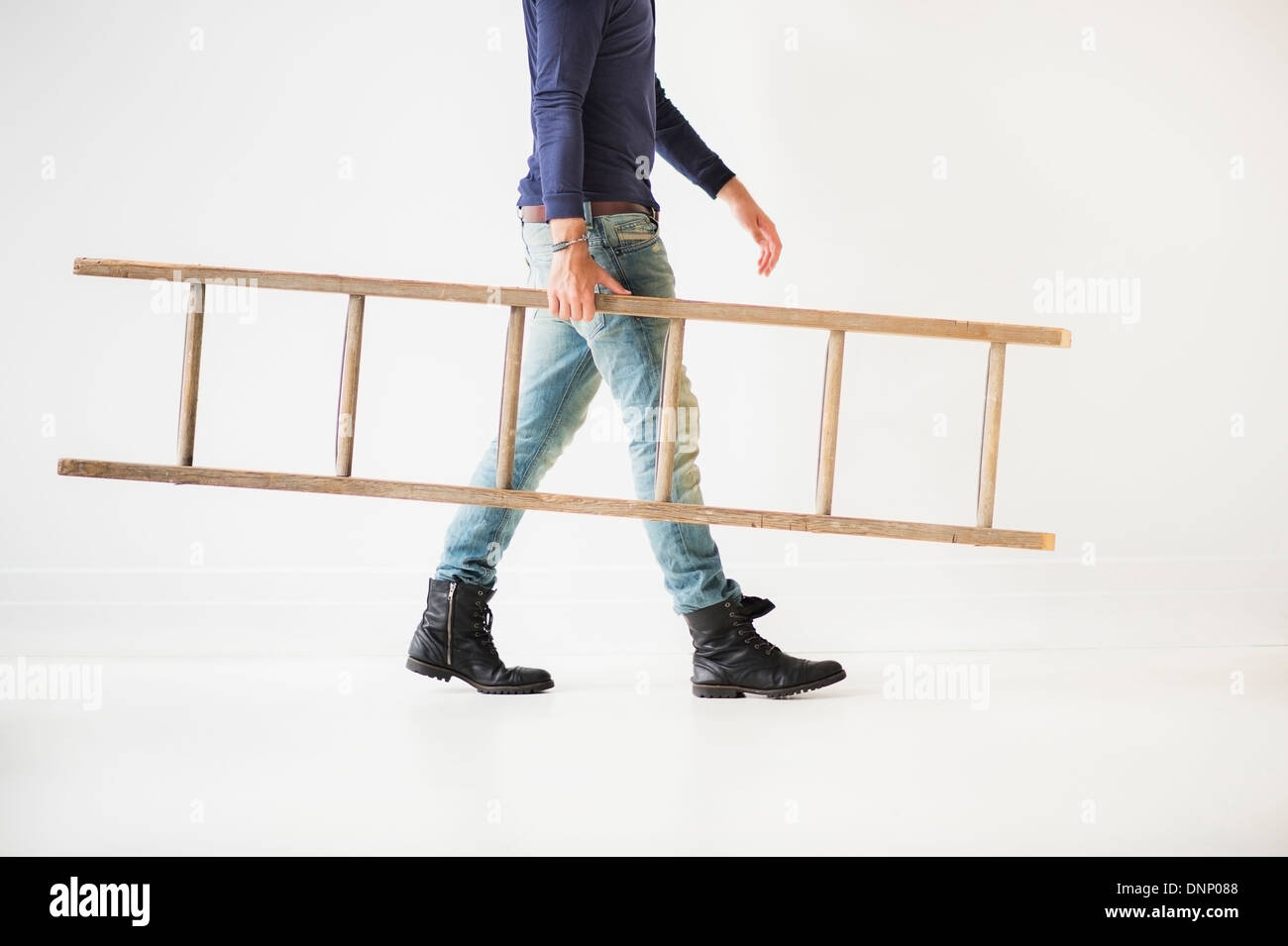 Low section of man carrying ladder Stock Photo - Alamy