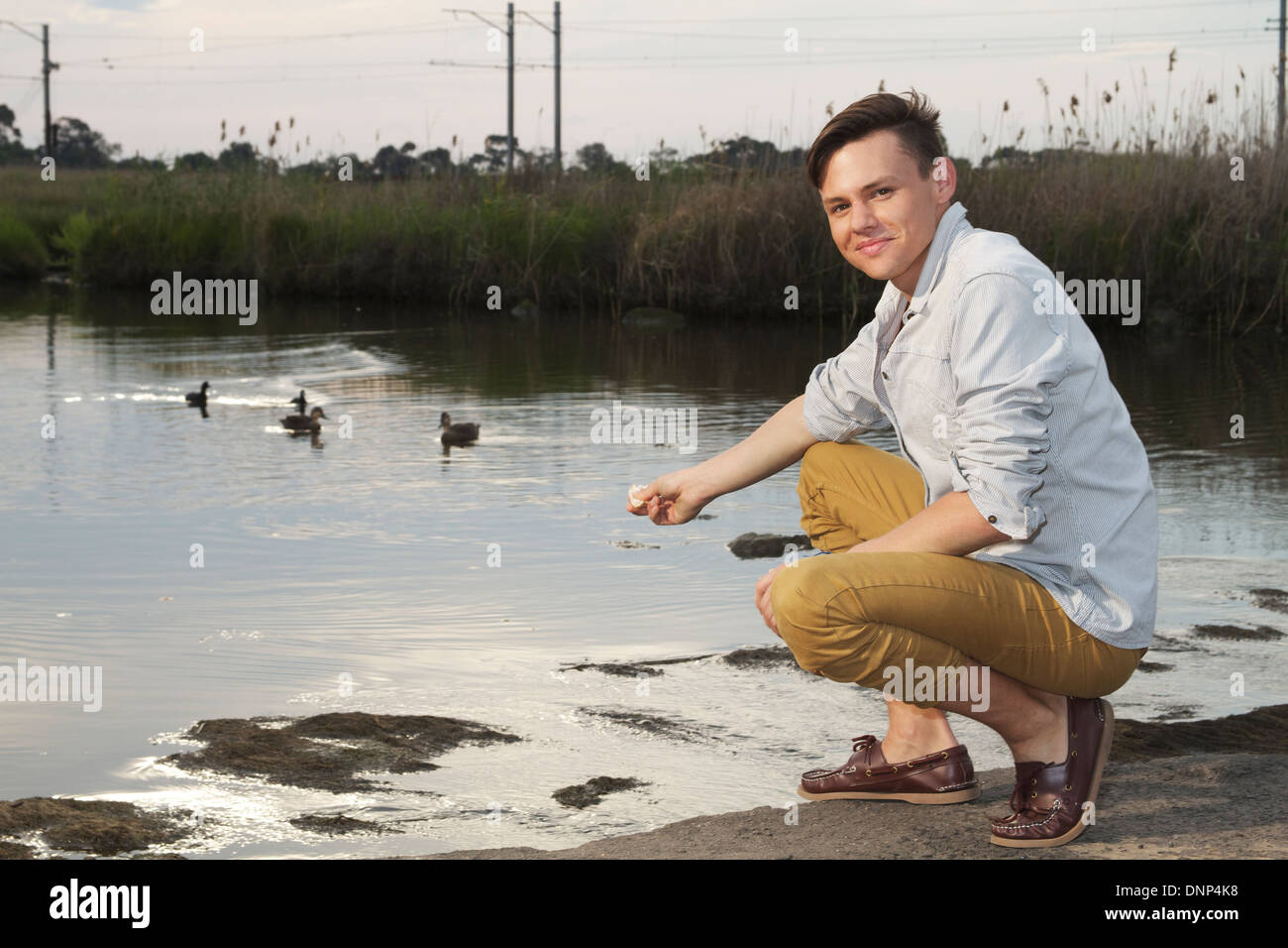 young man feeding the ducks Stock Photo - Alamy
