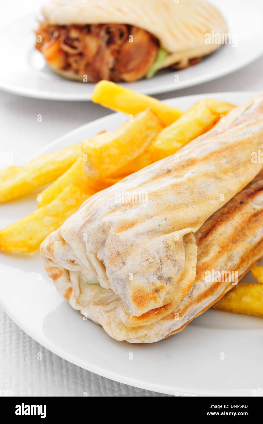 closeup of a durum kebab with fries and a doner kebab in the background ...