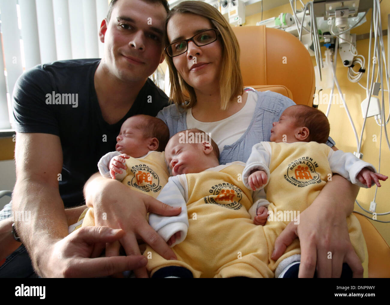 The triplets (L-R) Till, Max and Ben lie in the arms of their parents ...