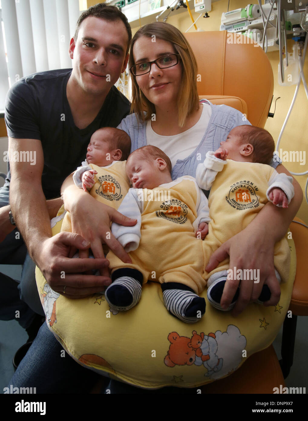 The triplets (L-R) Till, Max and Ben lie in the arms of their parents ...
