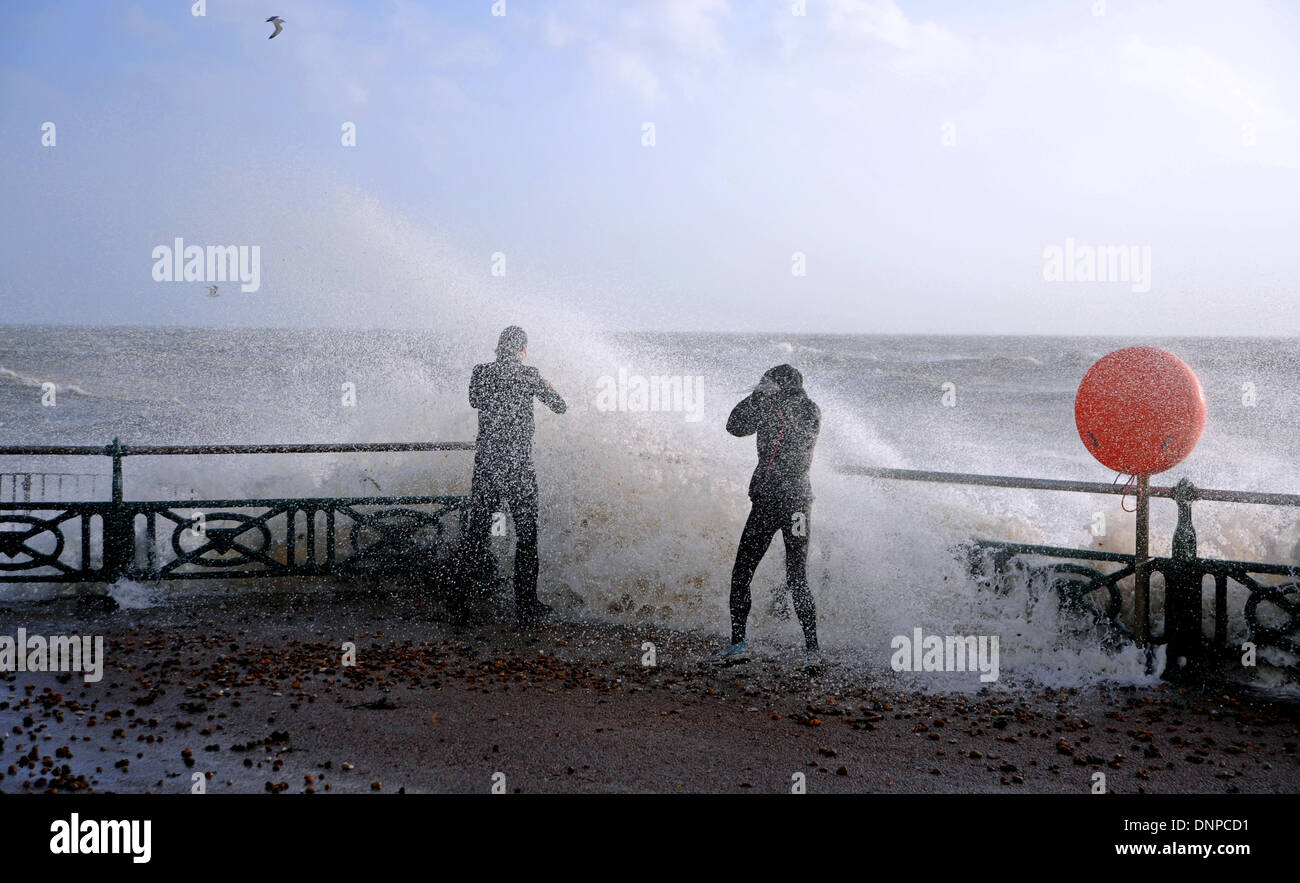 A couple get caught by a wave breaking over the promenade in Hove today ...